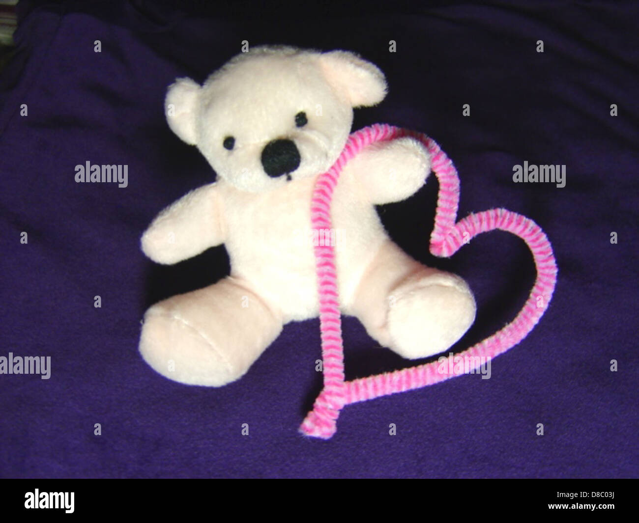 This image features a soft, white teddy bear holding a small heart ...