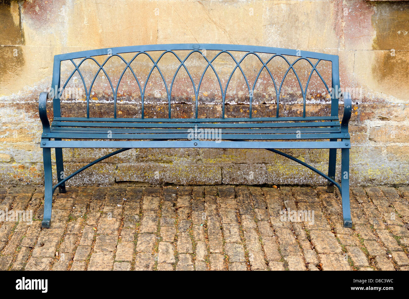 Empty iron bench on cobblestones Stock Photo - Alamy