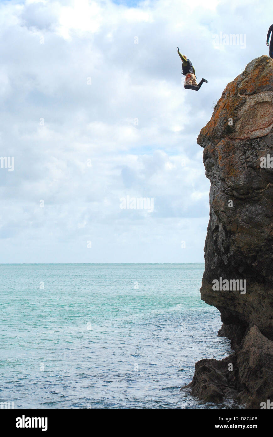 Man jumps off of rocky cliff into sea Stock Photo - Alamy