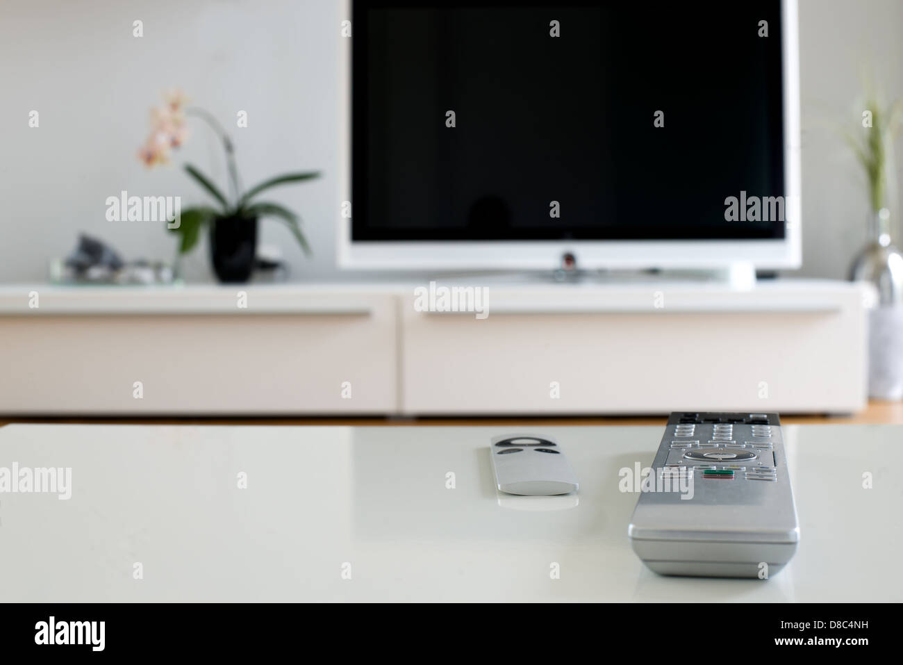 two remotes on white table in front of television Stock Photo - Alamy