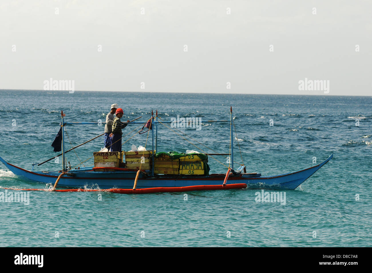Filipino fishermen in a boat in the sea near a coastal town of Puerto ...