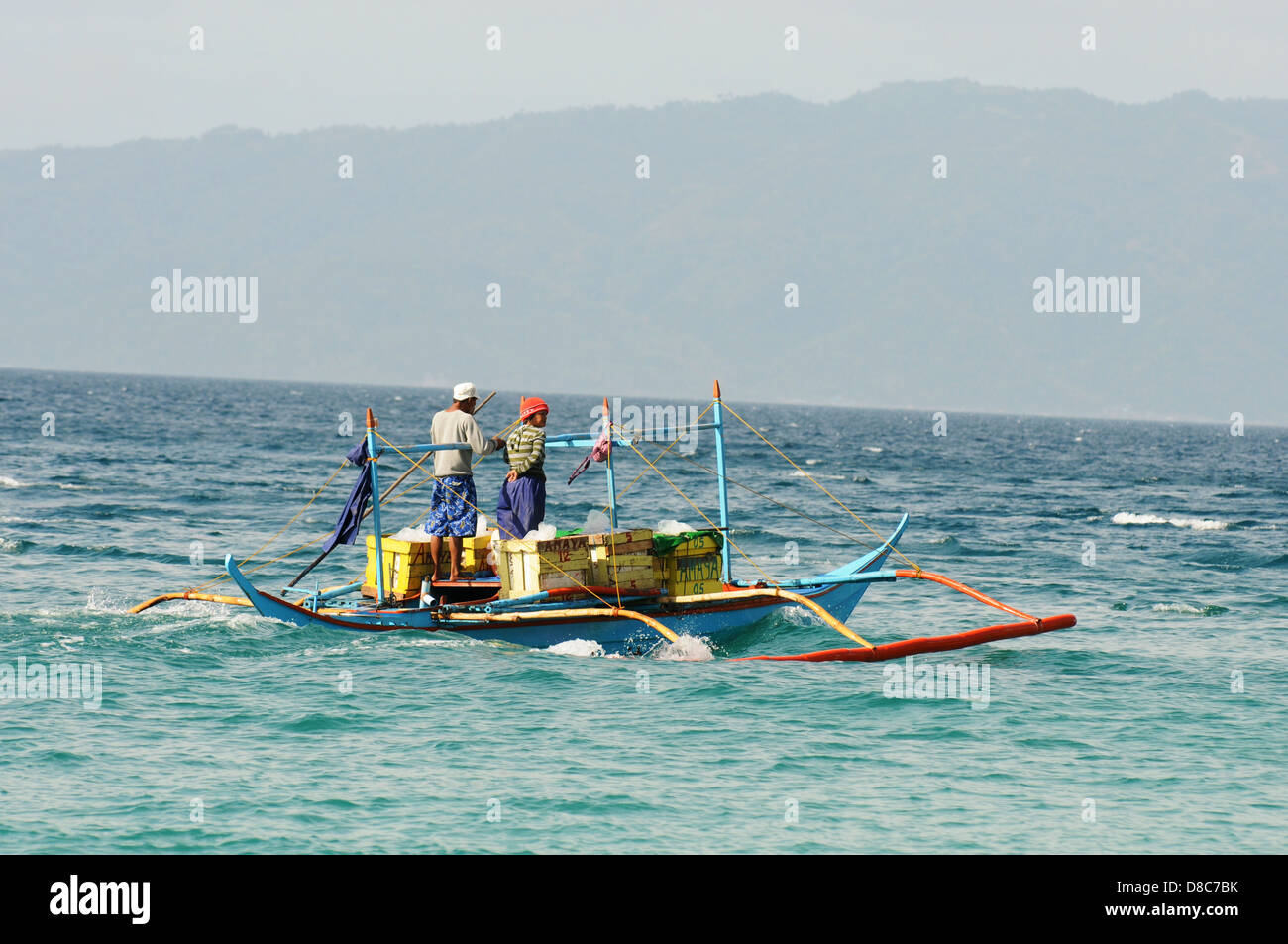 Filipino fishermen in a boat in the sea near a coastal town of Puerto ...