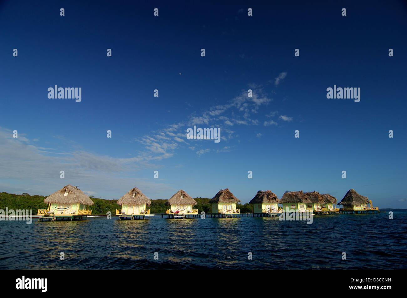 Thatch roofed bungalows on stilts in lagoon at Colon Island Stock Photo ...
