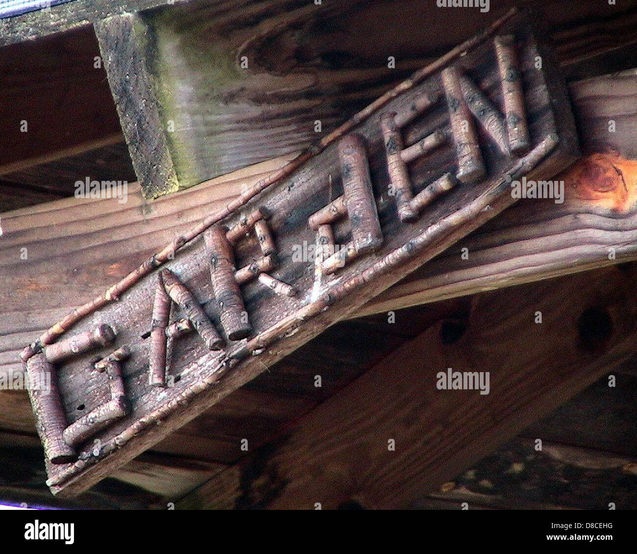 A garden sign stands at an angle, creating a slightly askew view. The ...