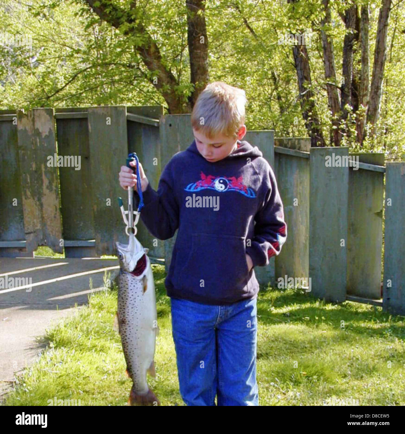 A little boy proudly holds a large fish, showing off his catch. The ...