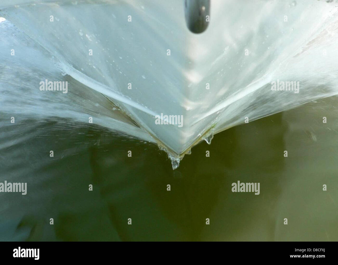 A boat cuts through the water, creating a wave at the front. The boat’s ...