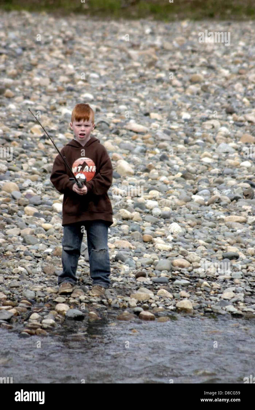 A young boy fishing in a natural outdoor setting, with a fishing rod in ...