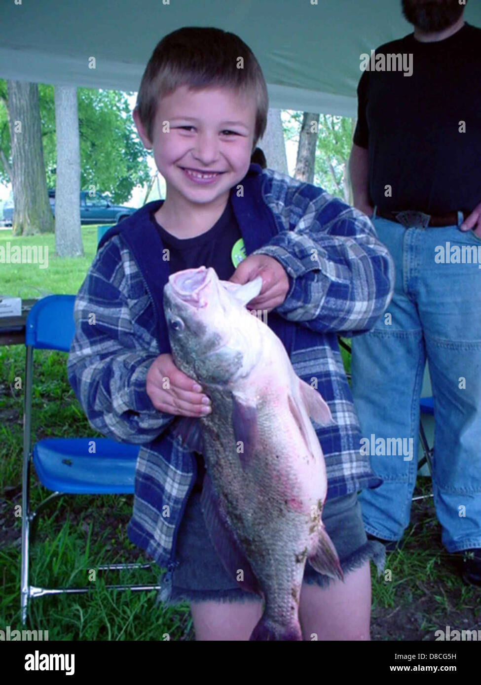 A young boy proudly holding a large fish, showcasing his catch. The ...