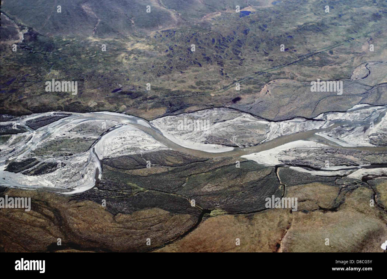 A braided river meanders through a valley, its channels split and ...