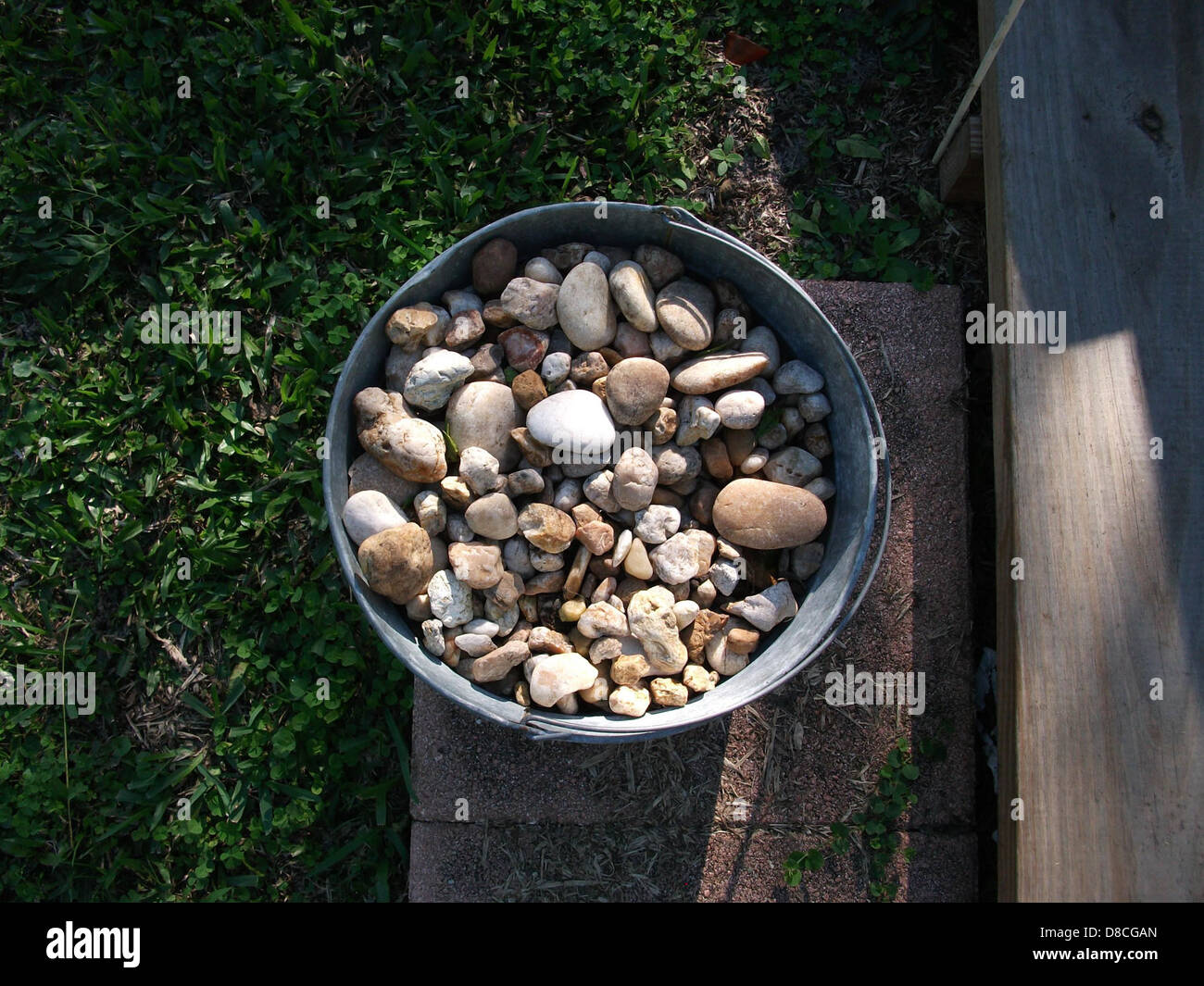 A bucket filled with various stones, ranging in size and texture. The ...