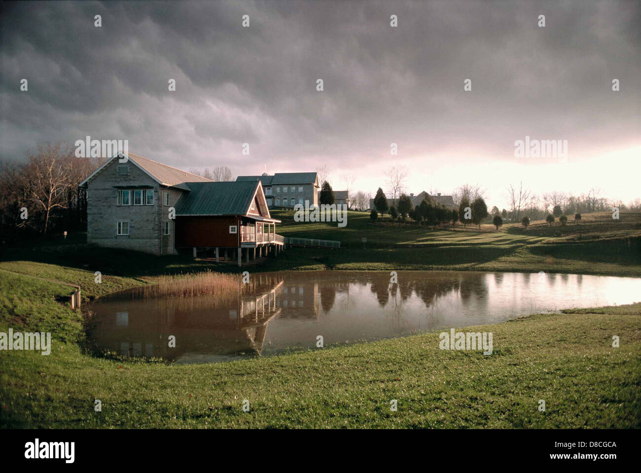 A building stands next to a pond, with stormy clouds gathering above ...