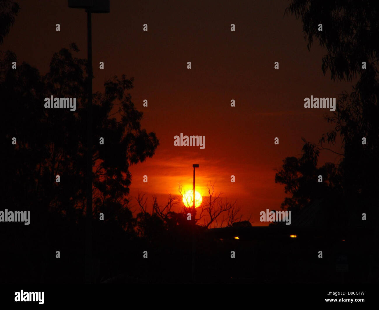 A bushfire sunset shows the dramatic sky tinged with deep red and ...