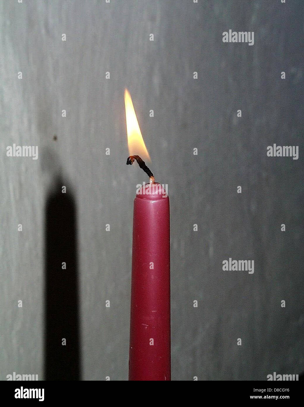A candle flame creates a soft, elongated shadow on a surface, providing ...