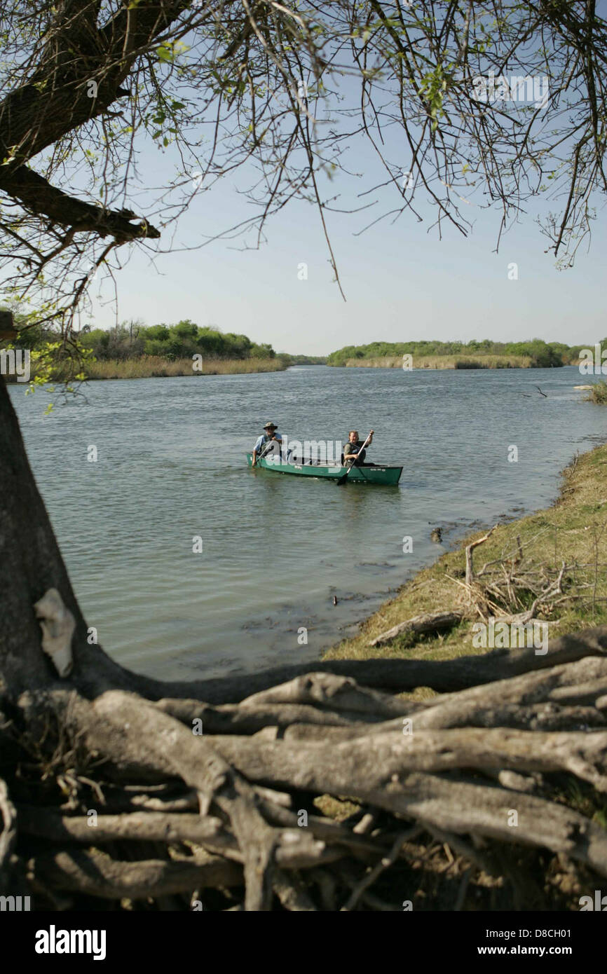 A group of people are seen canoeing on a calm river, surrounded by ...