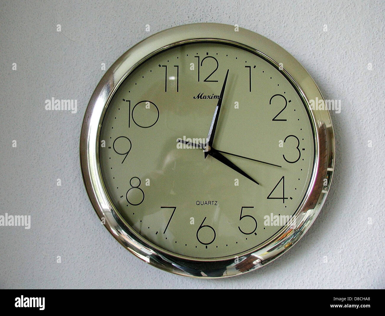 A close-up shot of a chrome clock with a sleek, modern design. The ...