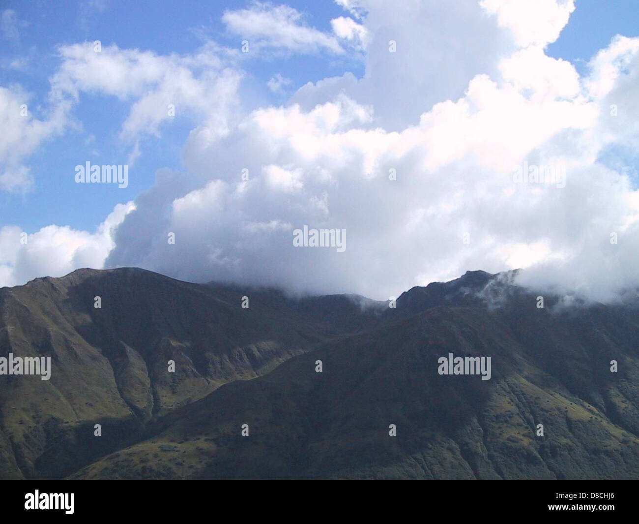 Clouds drift over a mountain, partially obscuring its peaks. The ...