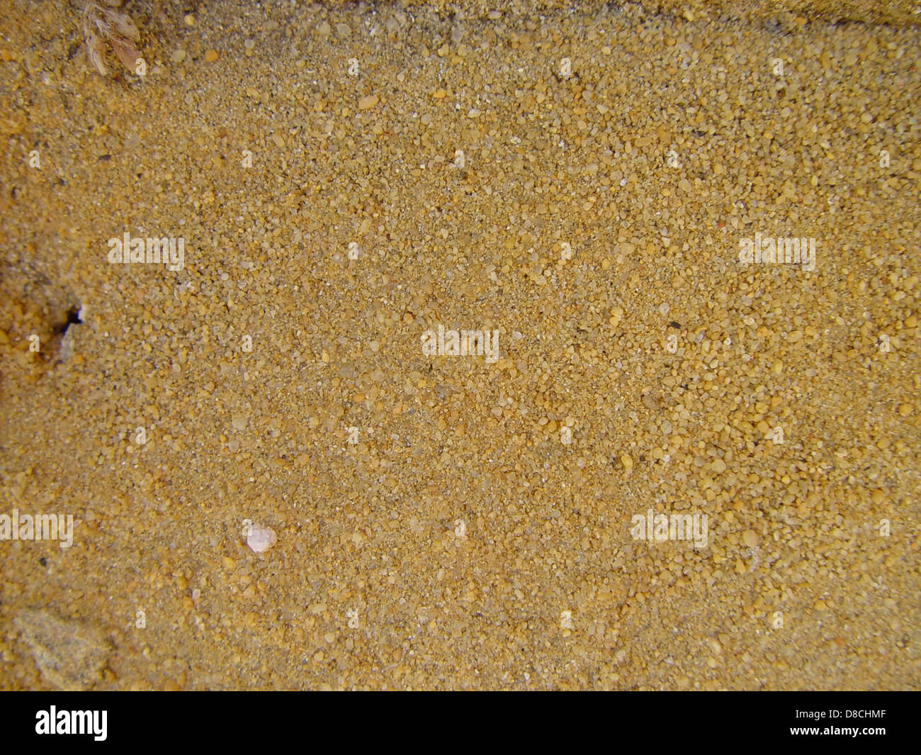 Coarse yellow sand is shown in the image, typically found in desert or ...