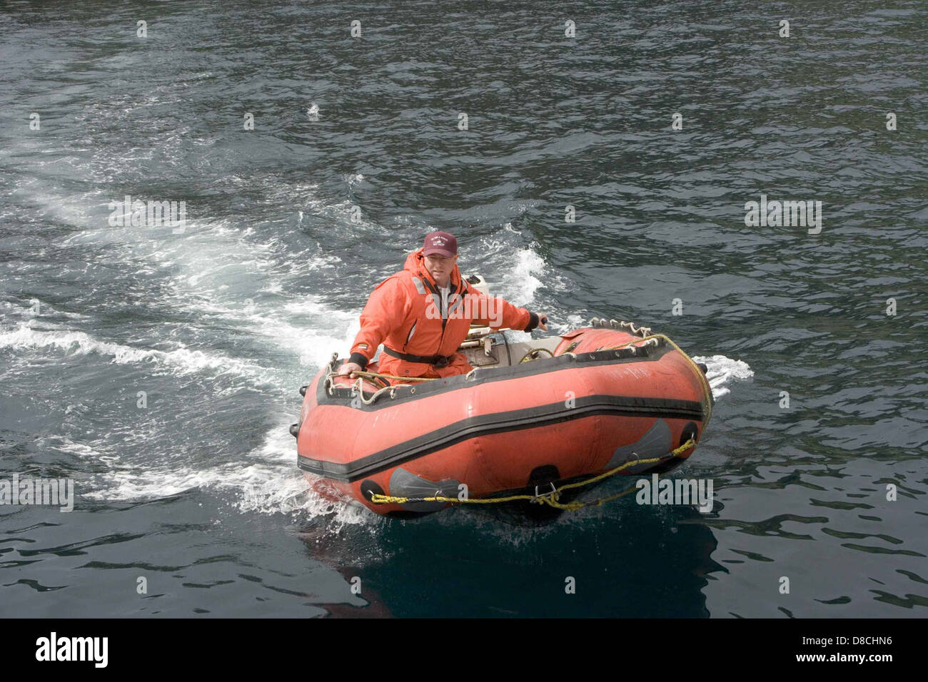 A Coastguard employee operating a boat skiff in open waters. The image ...