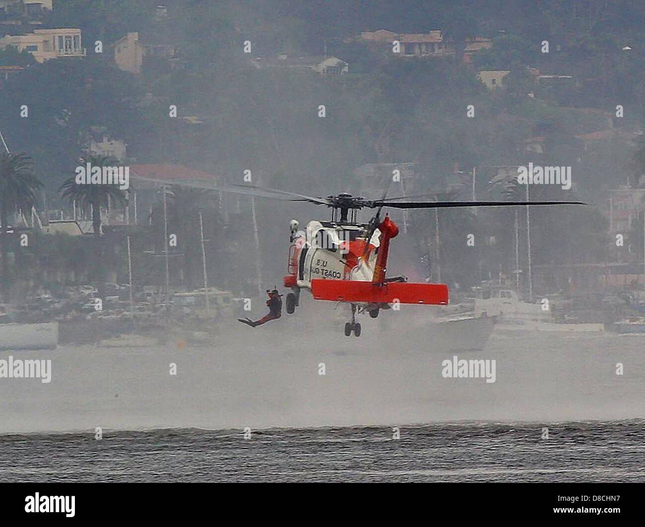 A Coast Guard helicopter hovers above the water as divers jump into the ...