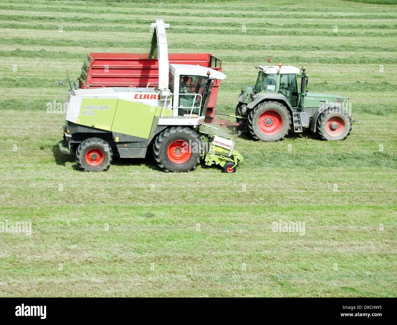 This image shows a combine harvester and tractor working together in a ...