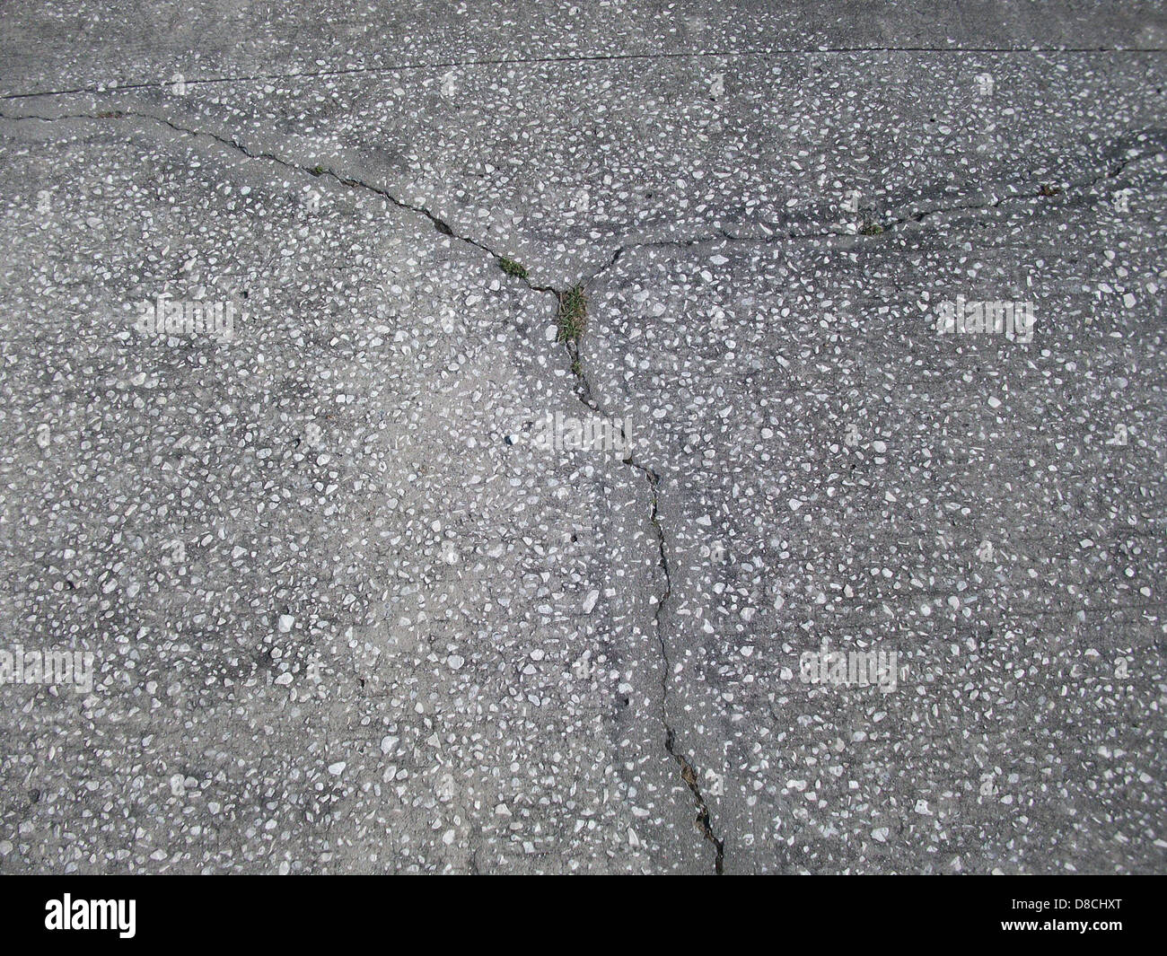 A close-up image of cracked concrete, showing the effects of aging or ...