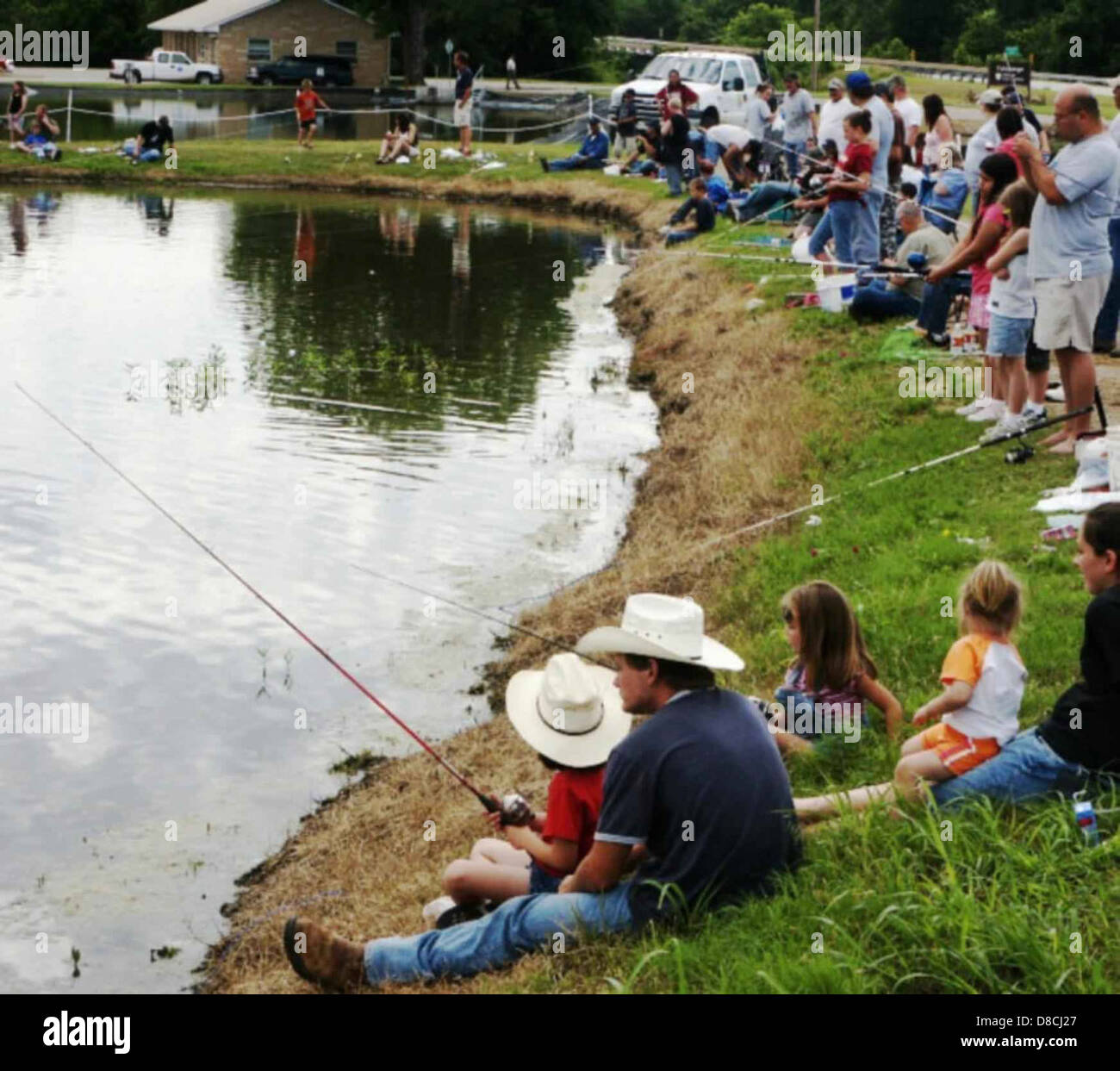 A group of cowboys fishing by a river or lake. The photo captures them ...