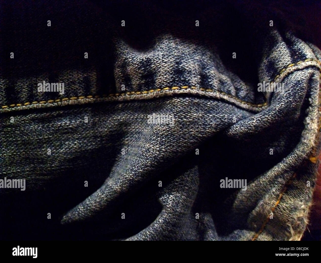 A pair of wrinkled denim jeans are shown, with noticeable creases and ...