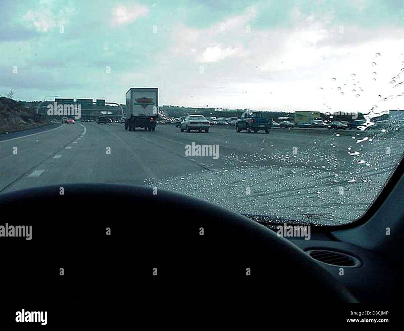 Cars drive through a rainstorm on a wet road, demonstrating the ...
