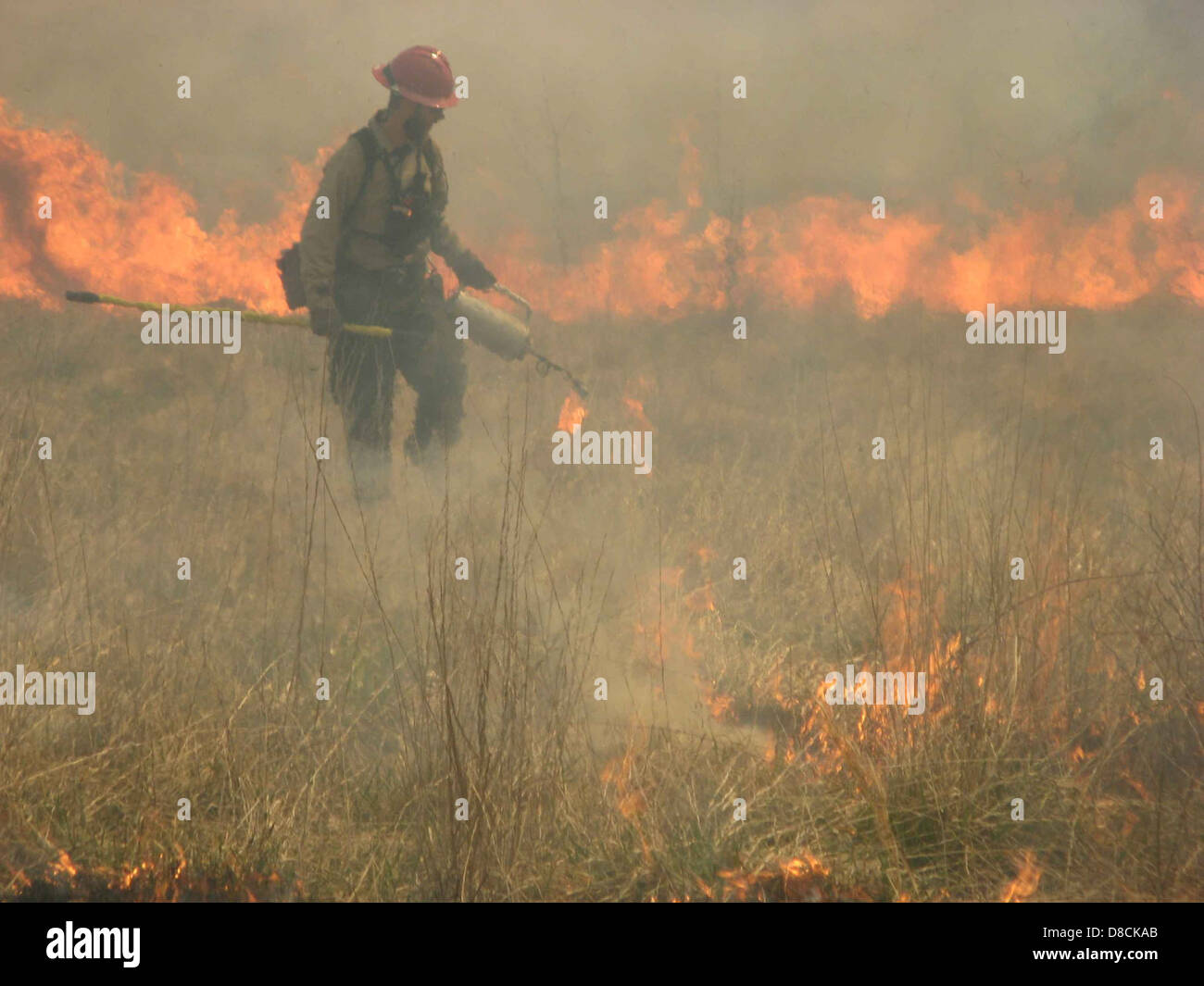 A firefighter in full gear is seen battling a blaze, working to ...