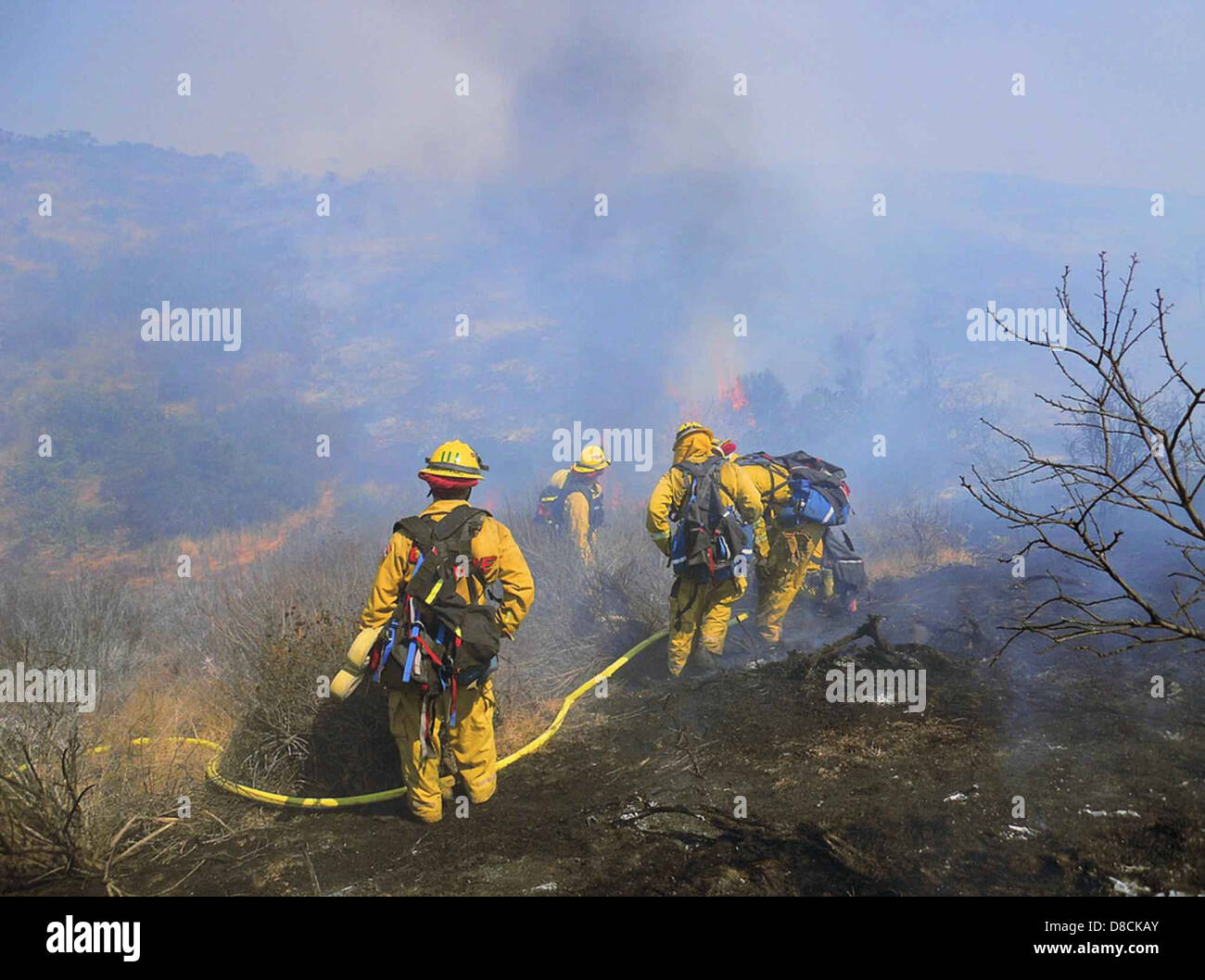 This image depicts a team of firemen actively battling a fire, with ...