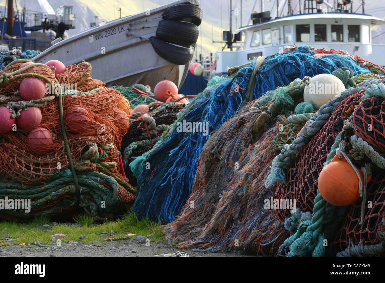 A pile of fish nets at a harbor, with several ships docked nearby. The ...