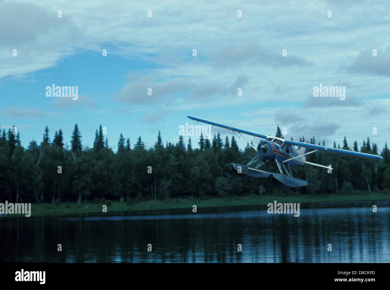 A floatplane is shown flying over a body of water. The image captures ...