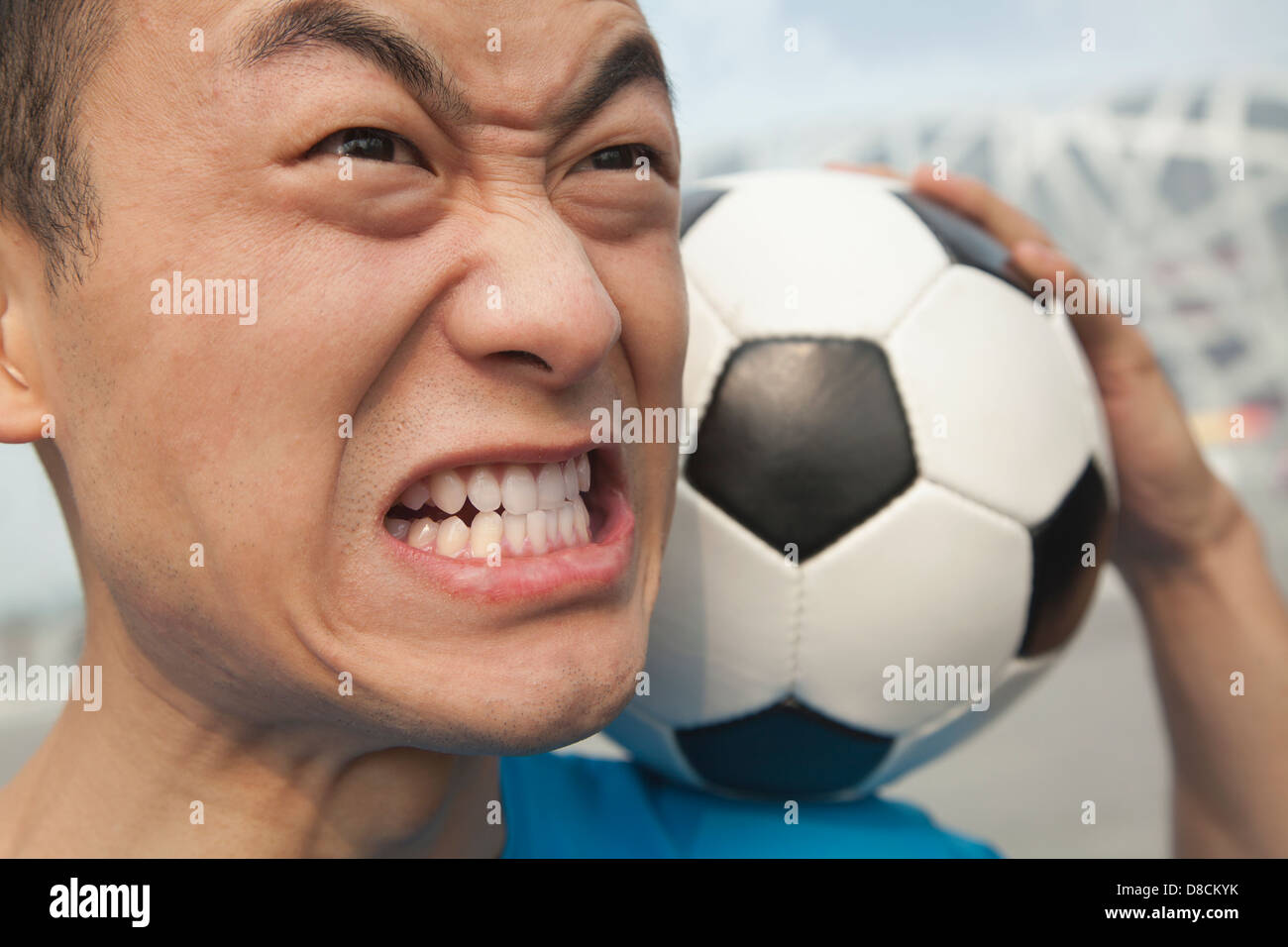 Close up of angry young man holding a soccer ball Stock Photo - Alamy