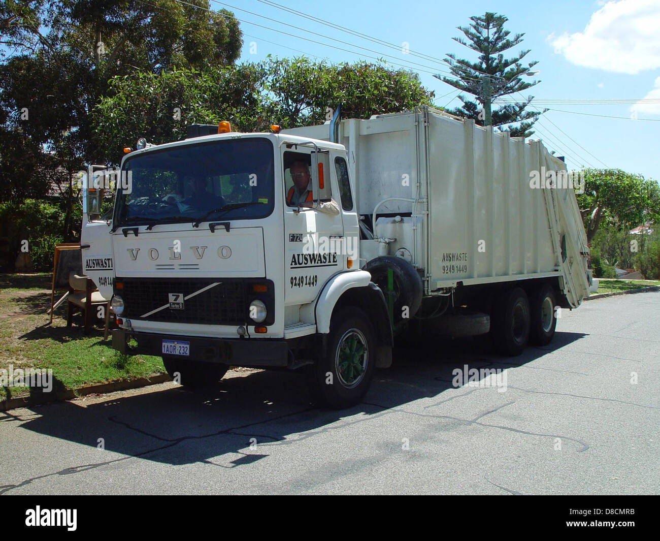 A stock photo of a garbage truck in operation, collecting waste from a ...