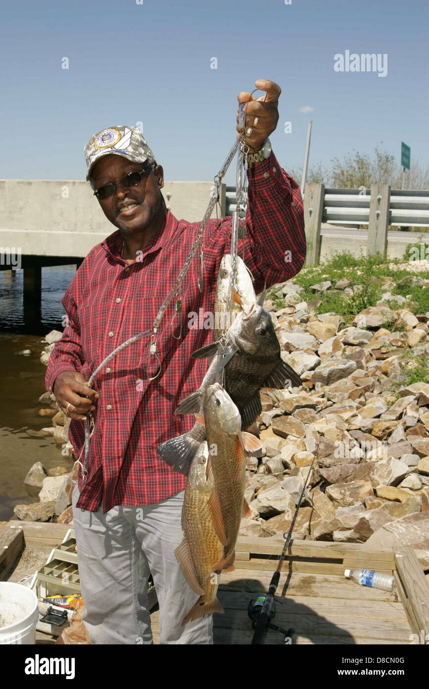 A man proudly displays the catch of the day, a fish caught during a ...