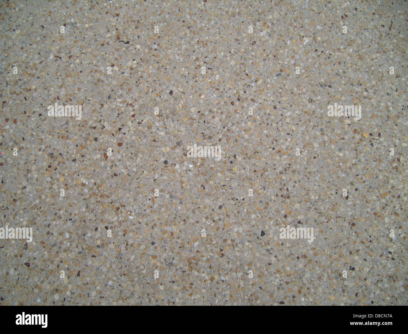A close-up of gravel embedded in concrete, highlighting the texture and ...