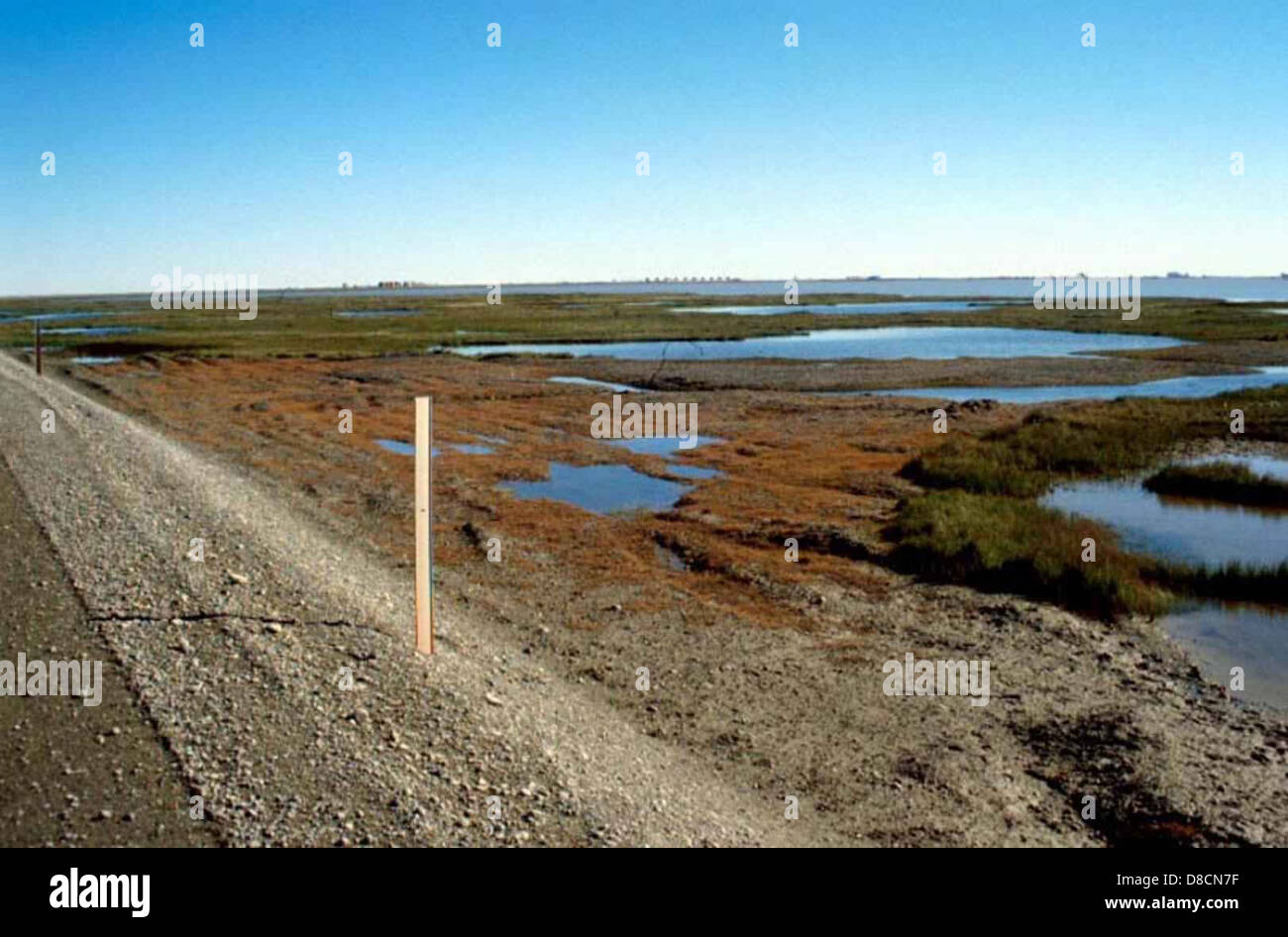 The image features a gravel road with oil fields visible on the north ...