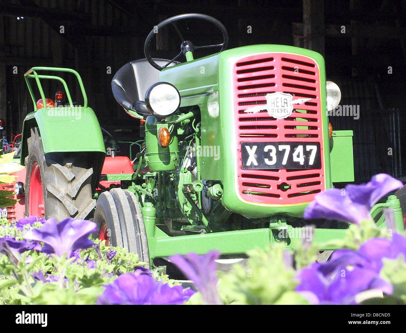 A vintage green tractor stands in a field, reflecting its classic ...