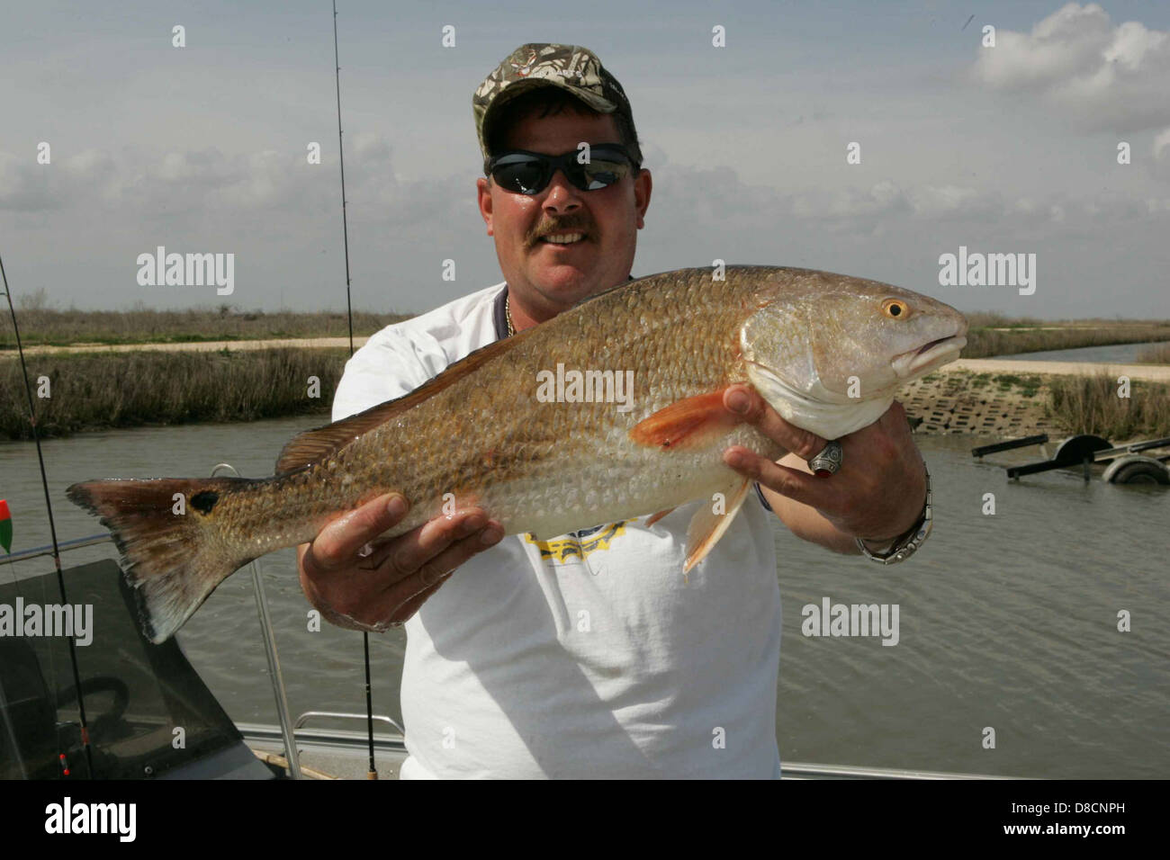 A fisherman smiling proudly as he holds up his catch, showing a large ...