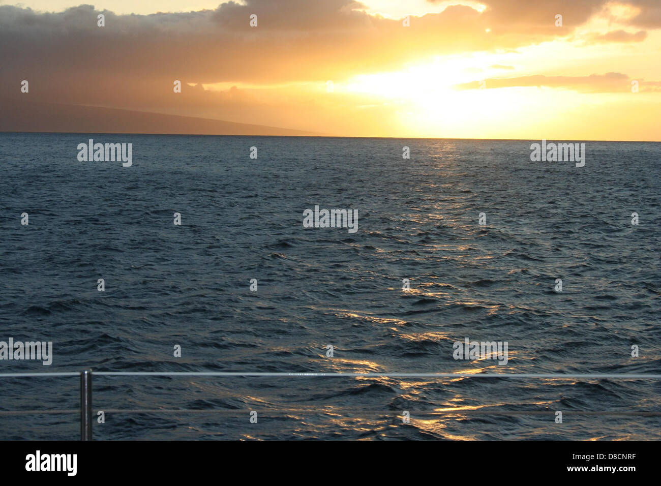 A Hawaiian sunset over the ocean, casting warm colors across the sky ...