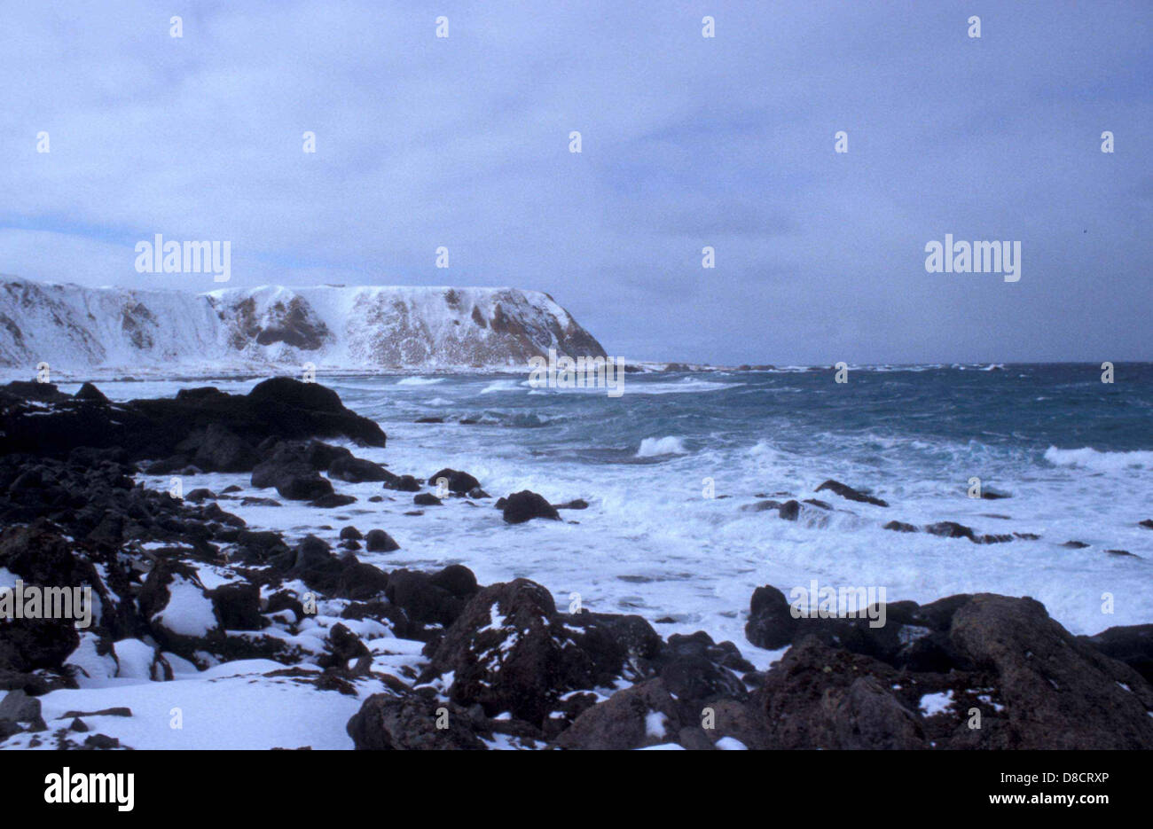 A coastal landscape featuring sea waves crashing against rocks, with ...