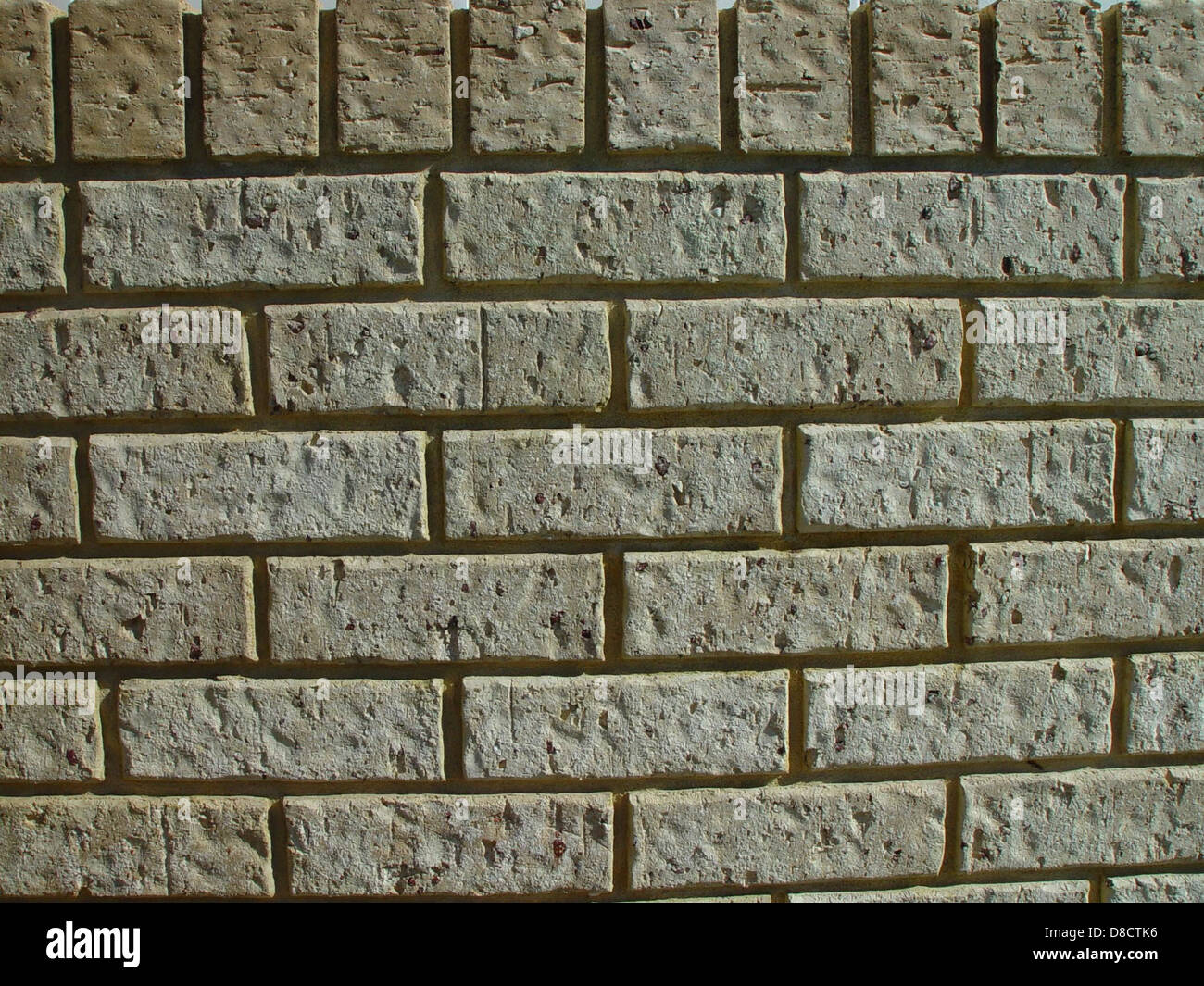 A light-colored brick wall, with a smooth and uniform surface. The ...