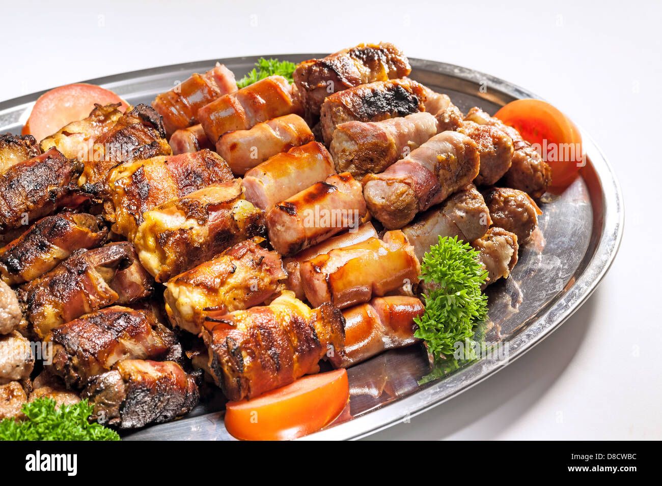 Various barbecue meat decorated and set on metal plate, studio isolated ...