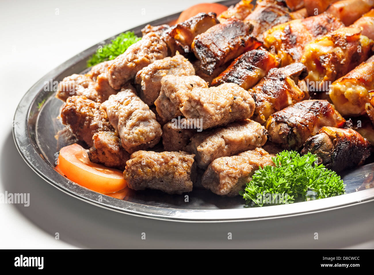 Various barbecue meat decorated and set on metal plate, studio isolated ...