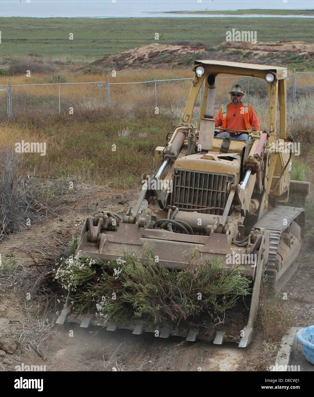 A man operates a bulldozer, moving earth in a construction site. The ...