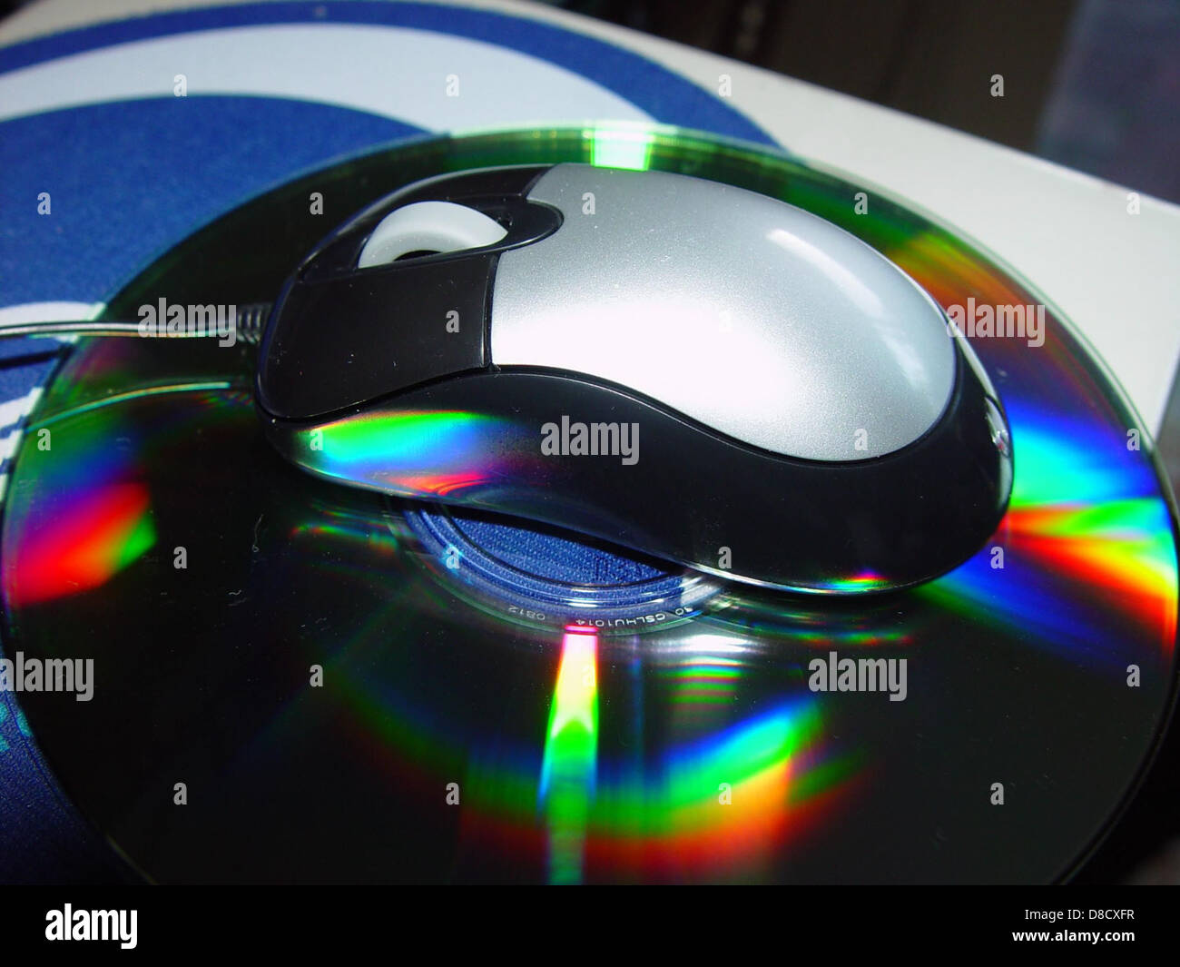 The image shows a mini mouse figurine placed on a CD, with rainbow ...