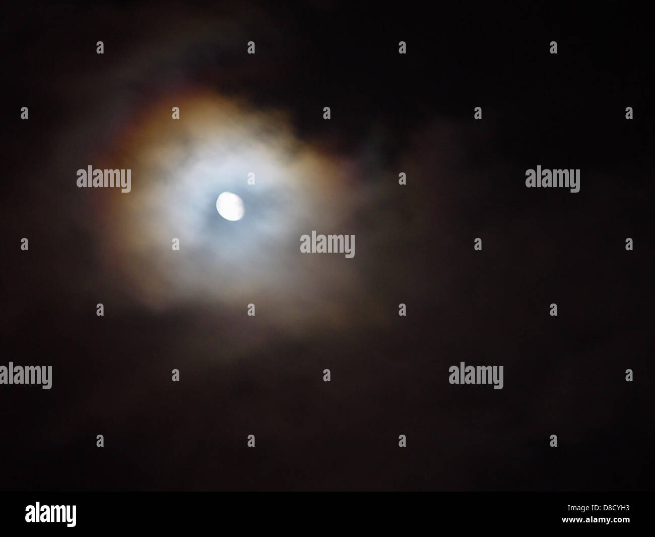 A moon partially obscured by clouds, creating a soft glow in the night ...