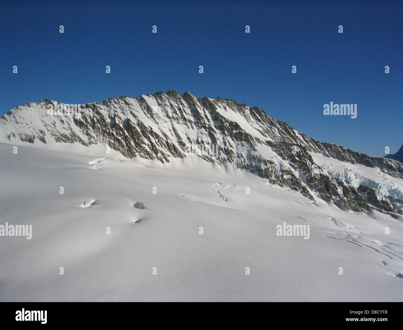 A winter scene showing a mountain clearing, covered in snow, with a ...