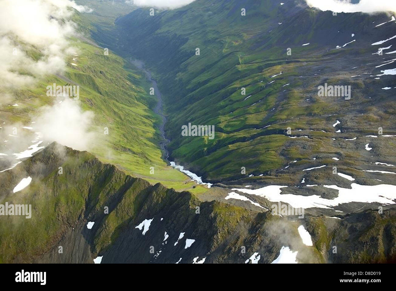 An aerial view of mountain peaks with a winding river valley below. The ...