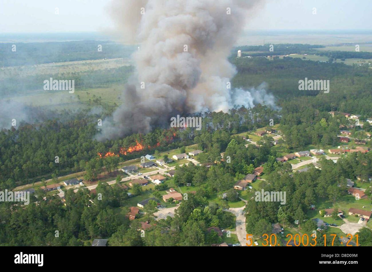 This image shows a forest fire approaching an urban settlement. The ...
